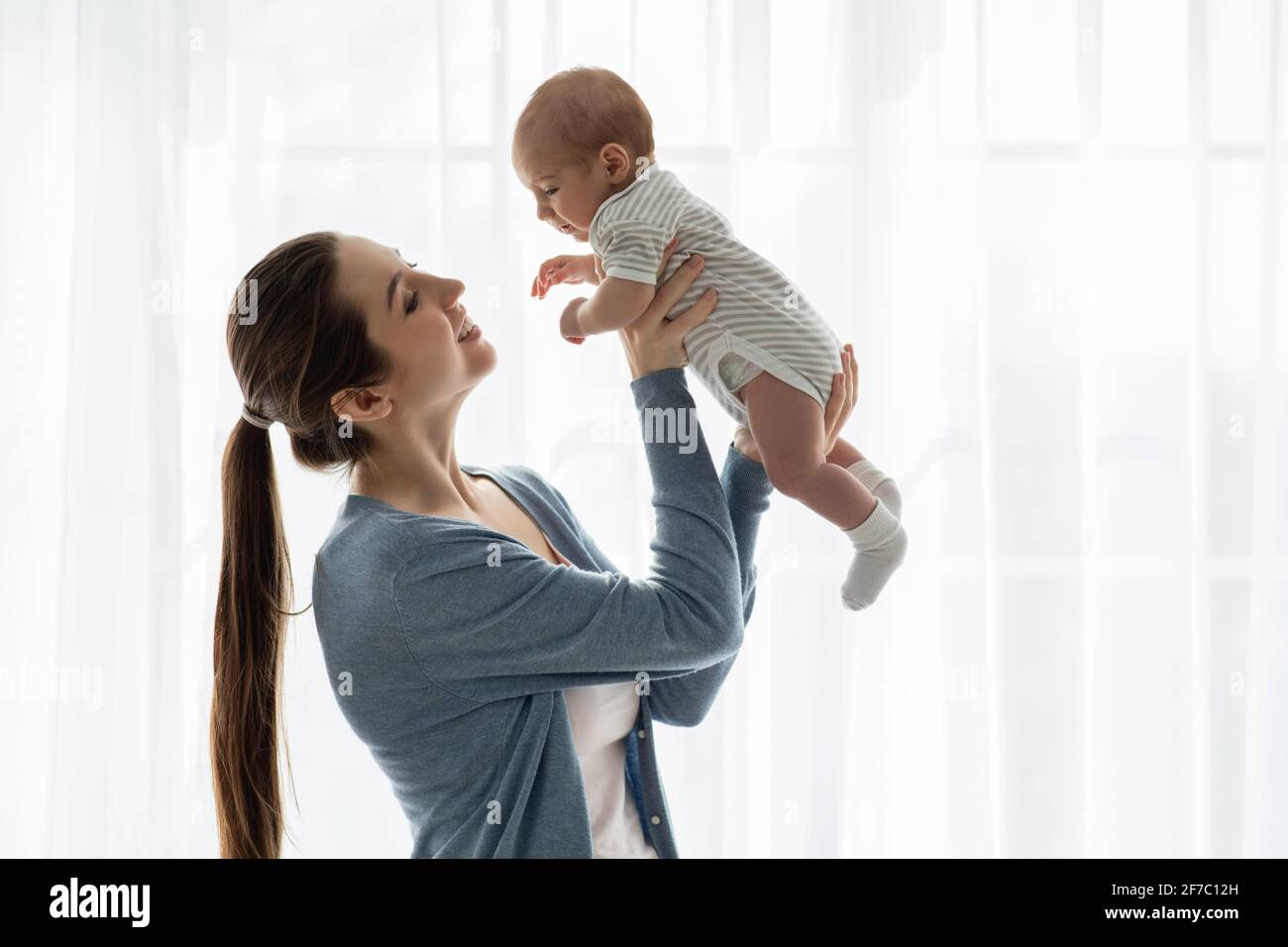 Happy young mom lifting her adorable little newborn baby in air Stock ...