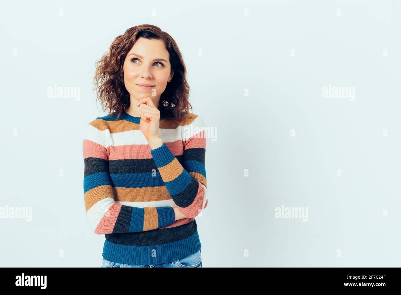 Happy young woman dreamily looking to the side smiling while standing ...