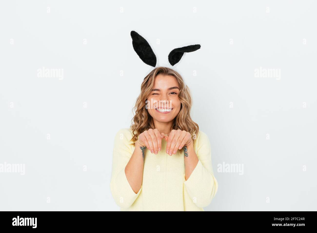 Portrait of playful young woman wearing bunny ears gesturing like ...