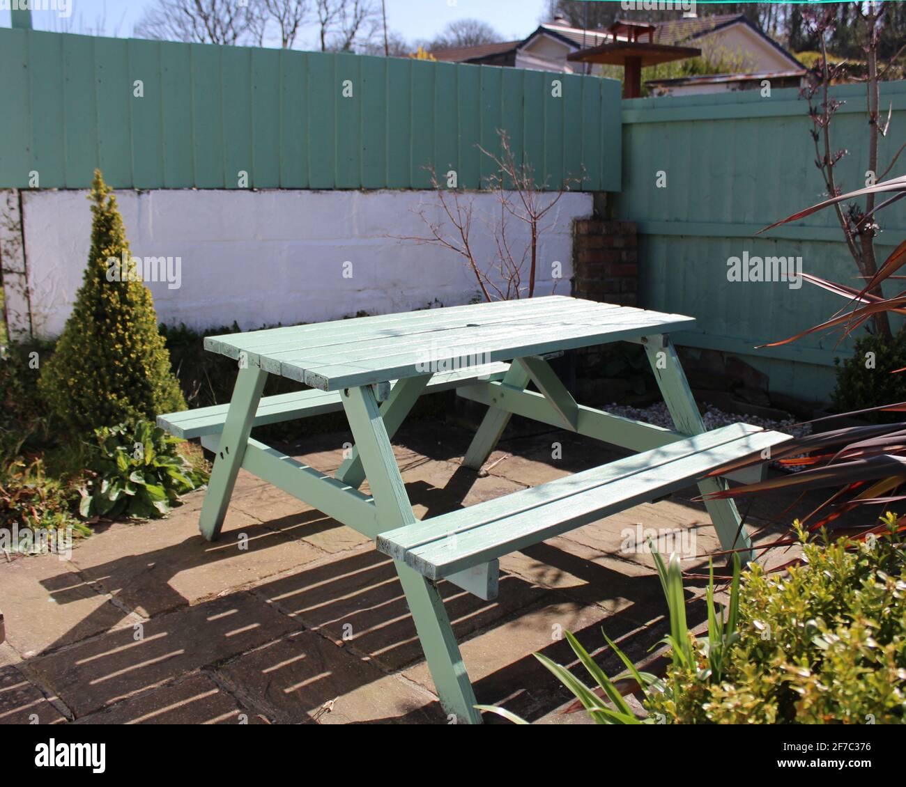 Secluded garden seating area with colourful turquoise picnic table on a ...