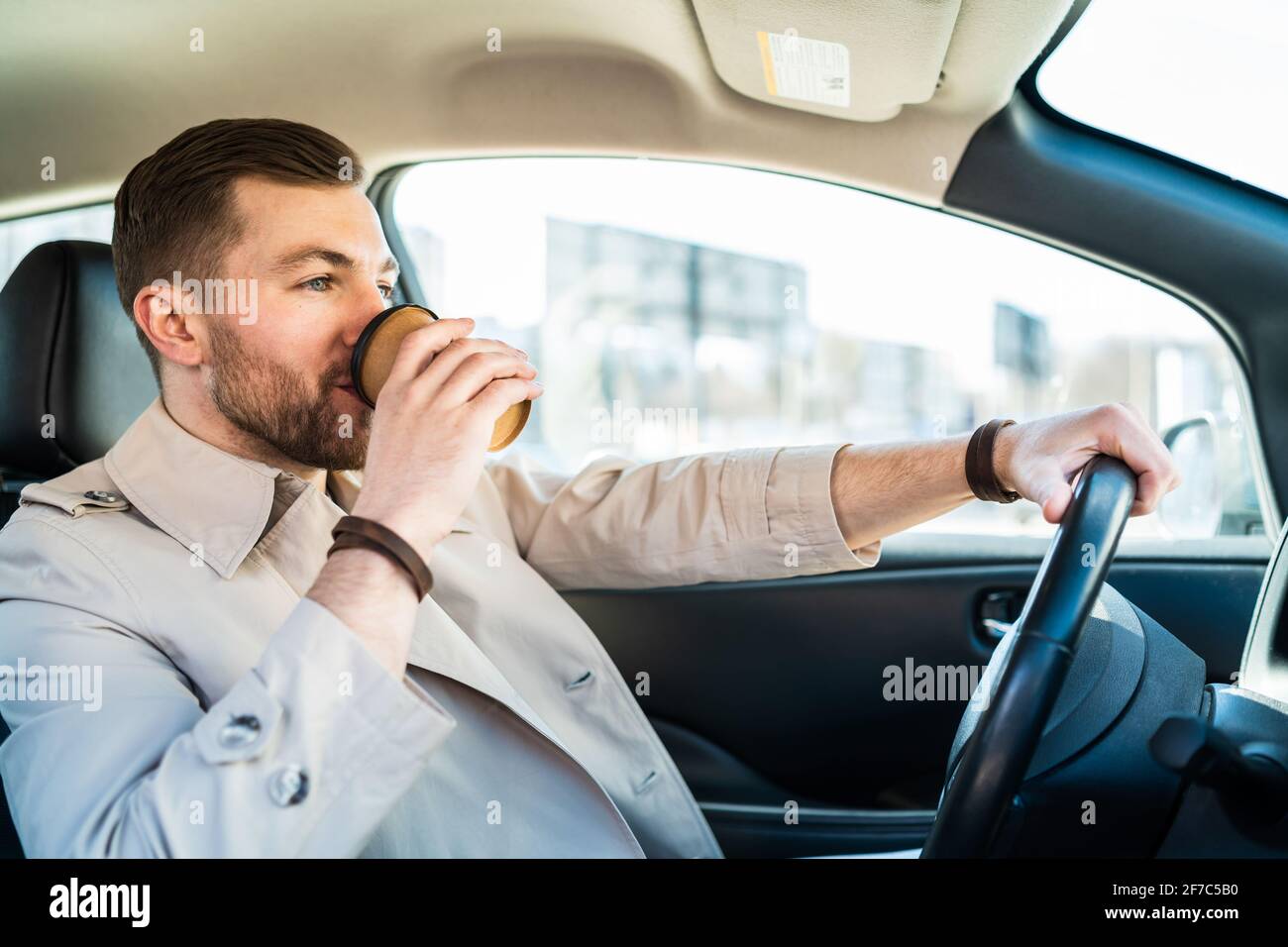 Man drinking morning coffee while driving car Stock Photo - Alamy
