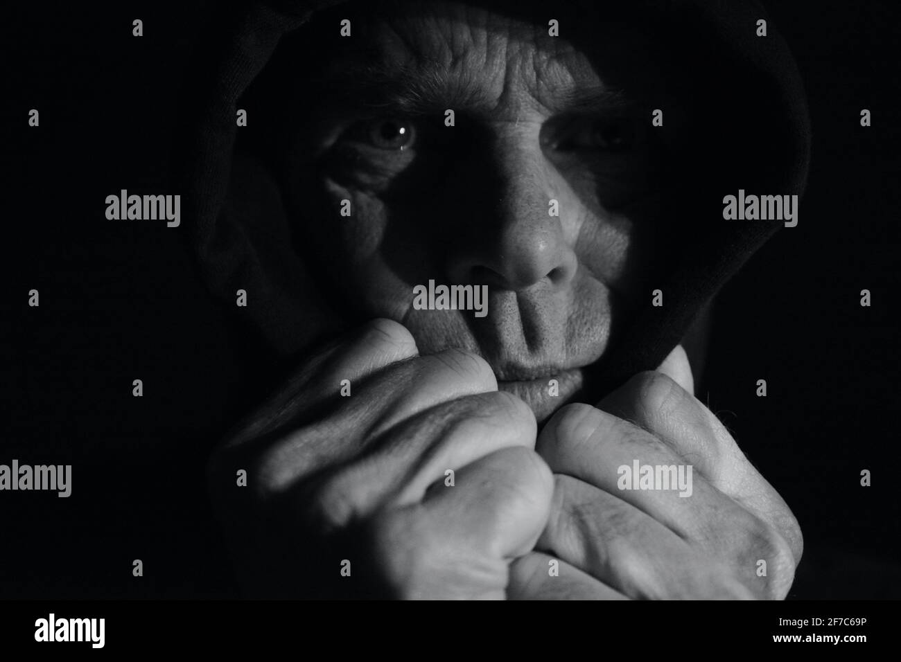 A monochrome headshot of mature male with a bald head and light shining ...