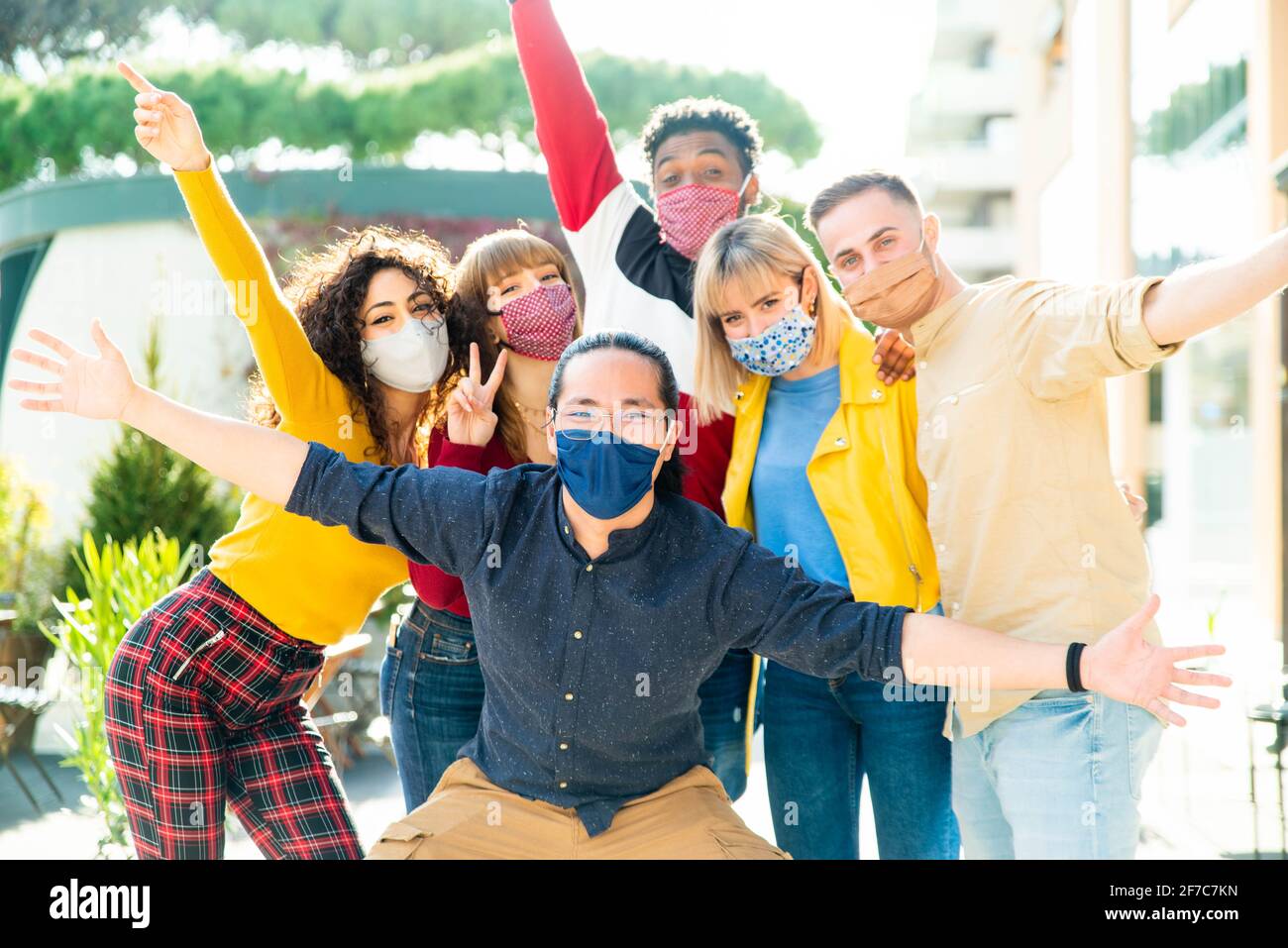 Group of multiracial people wearing protective face masks smiling at ...