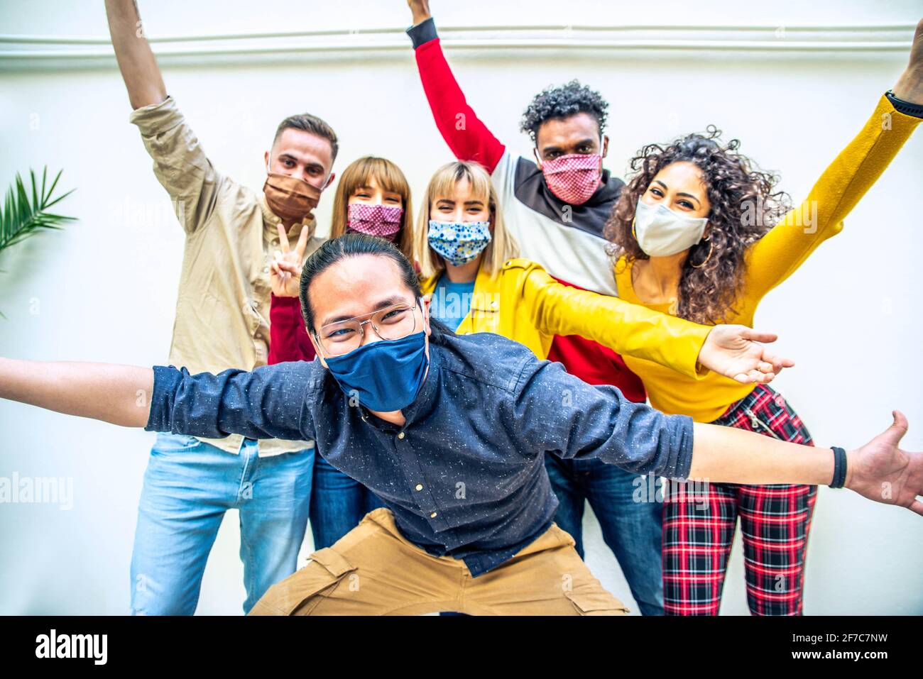 Multicultural people covered by protective face masks smiling at camera ...