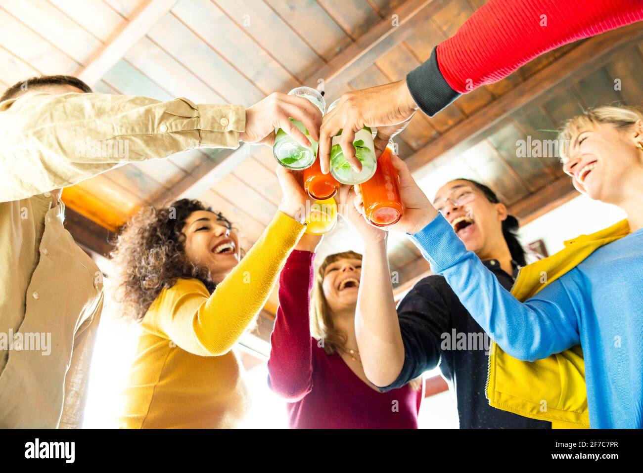 Multicultural friends cheering and drinking cocktails at bar restaurant ...