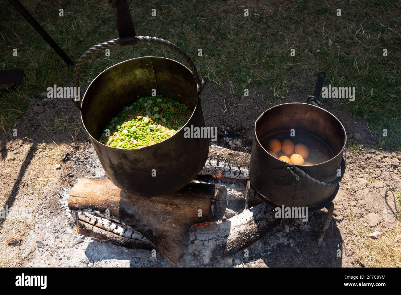 Medieval meal (peasant green pea stew, eggs) is prepared in cauldron on ...