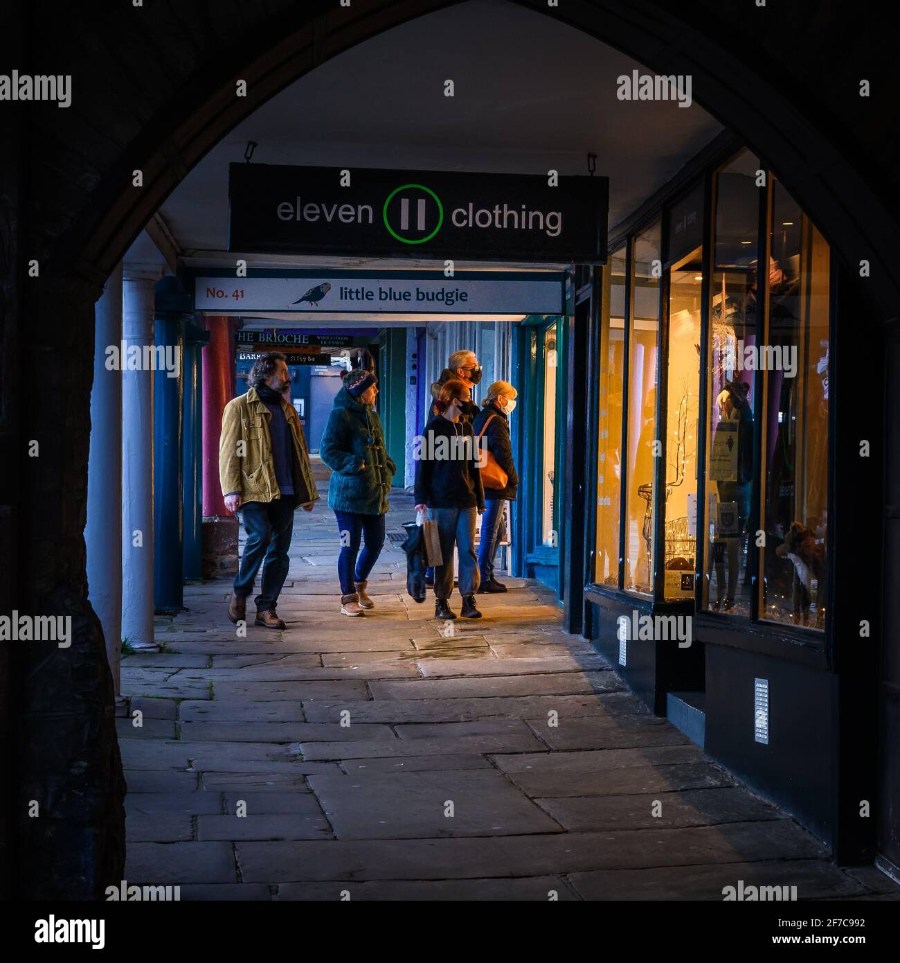 Shoppers looking at lit shop window in ancient town during pandemic Stock Photo - Alamy