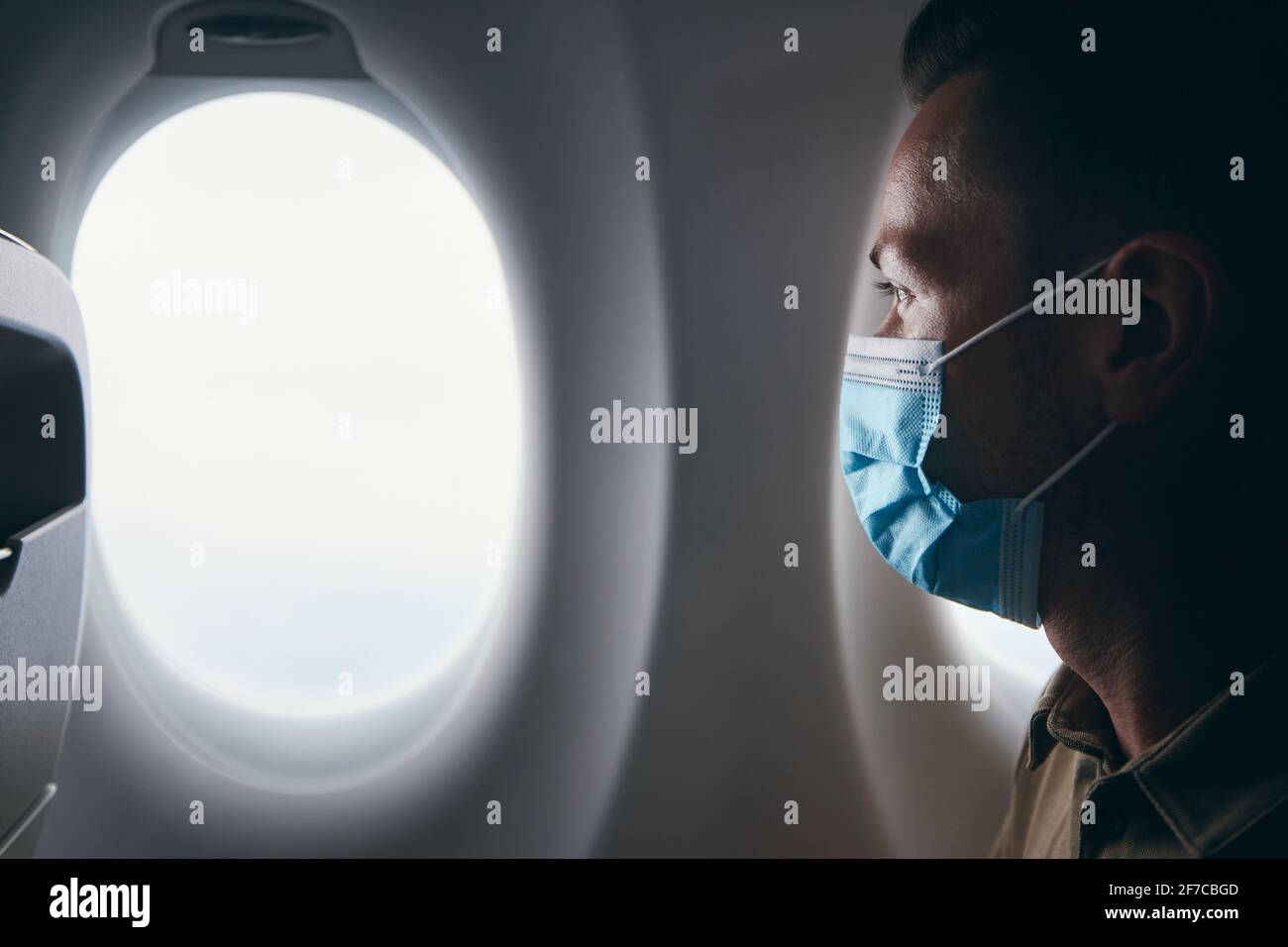 Man wearing face mask inside airplane during flight. Themes traveling ...