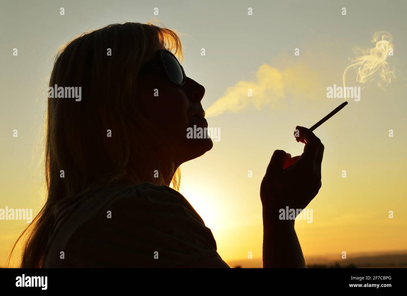 Woman smoking a cigarette at sunset Stock Photo - Alamy