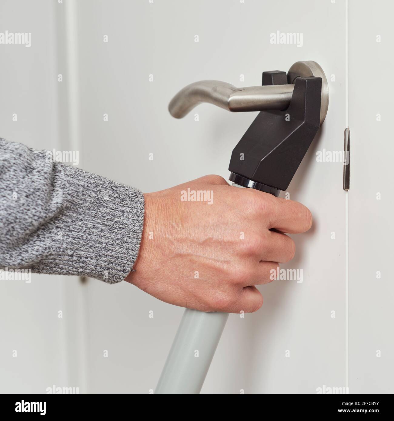 a young caucasian man secures the door of his house with a door blocker ...