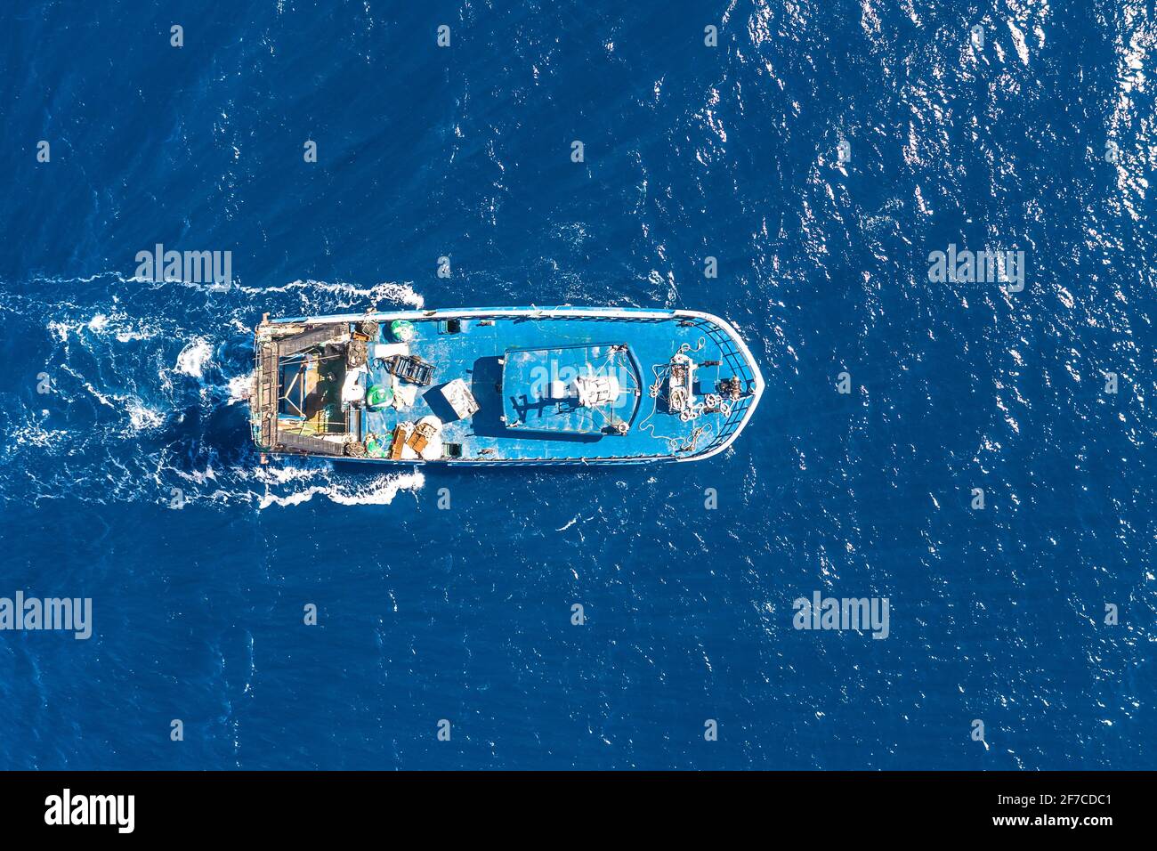 Fishing vessel boat floating in the blue sea, aerial view from above ...