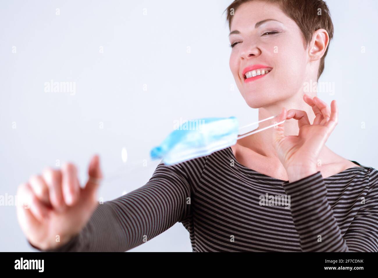 Beautiful woman with short hair throwing away face mask in a slingshot ...