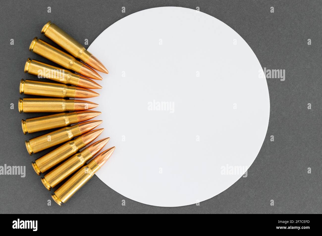 Bullets next to white circle on gray paper background. Cartridges 7.62 ...