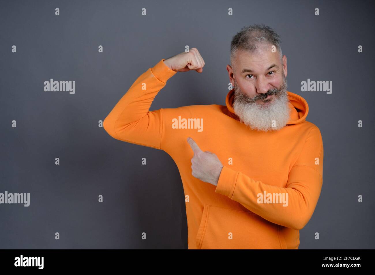 Mature Bearded Man Dressed Orange Hoodie Shows Muscles After Practising