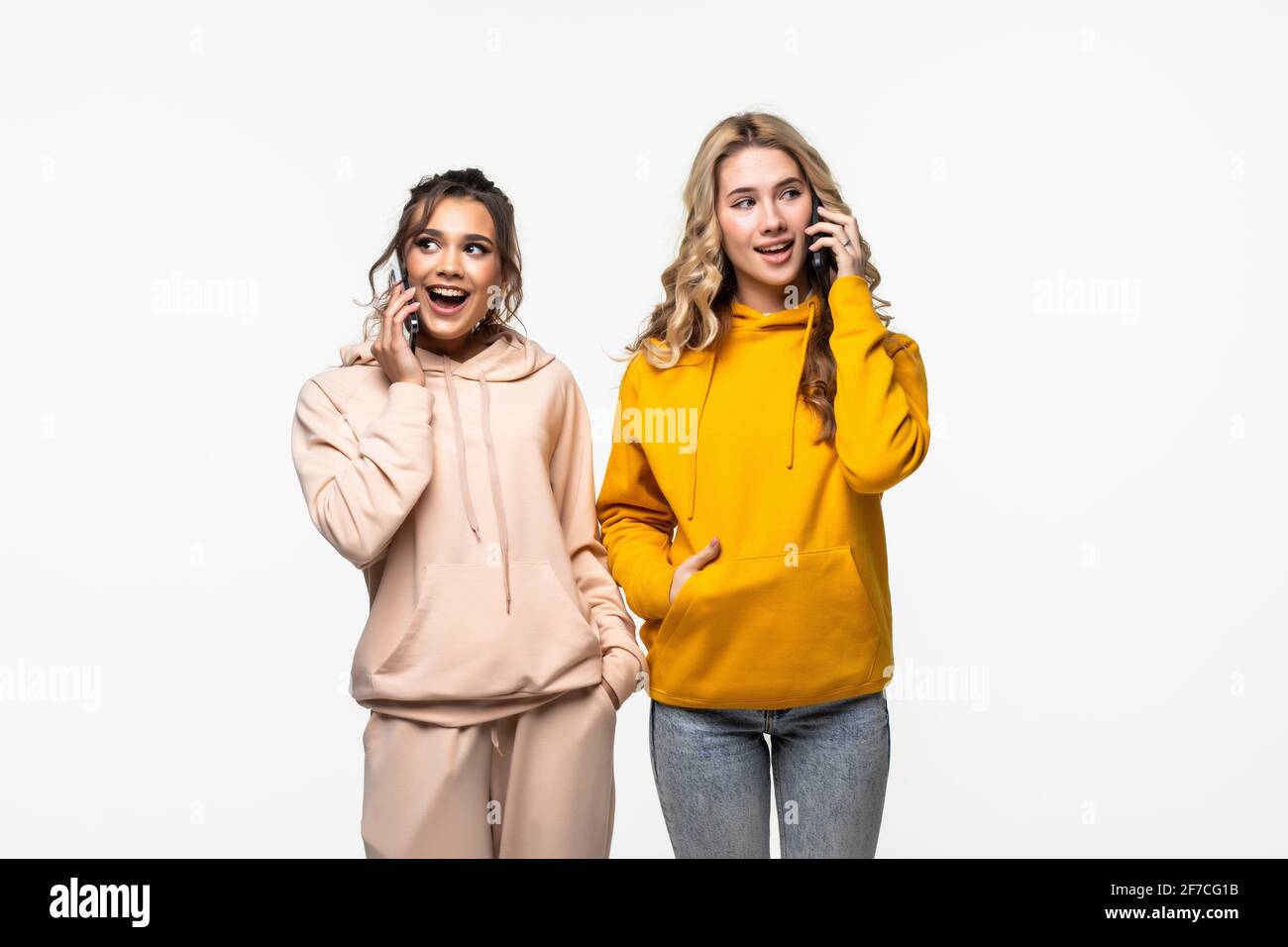 Two women talking on the phone on white background Stock Photo - Alamy