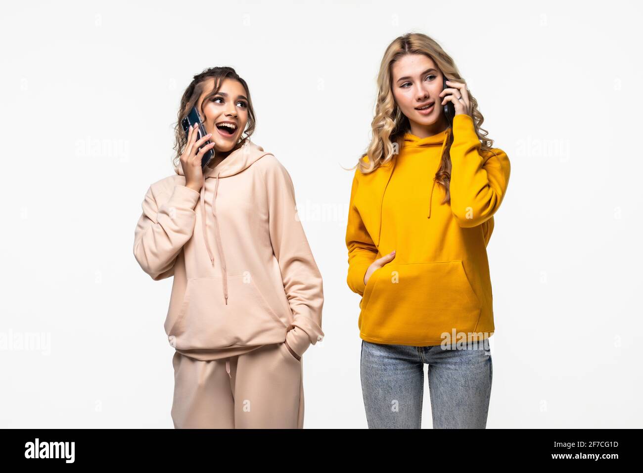 Two women talking on the phone on white background Stock Photo - Alamy