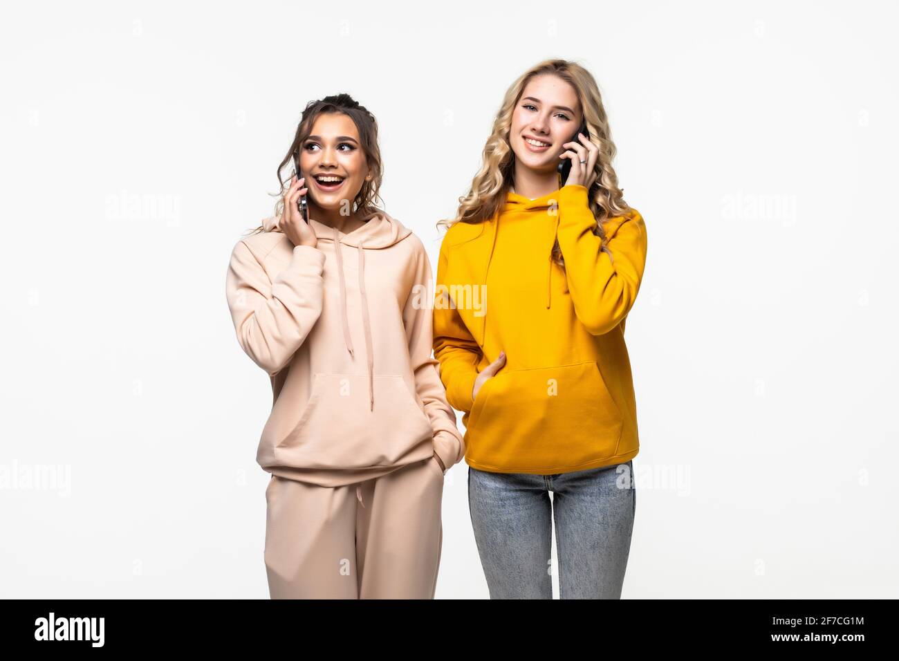 Two women talking on the phone on white background Stock Photo - Alamy