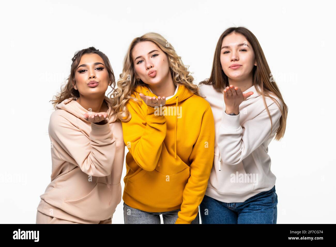 Three young beautiful mischievous ladies blowing kisses across their ...