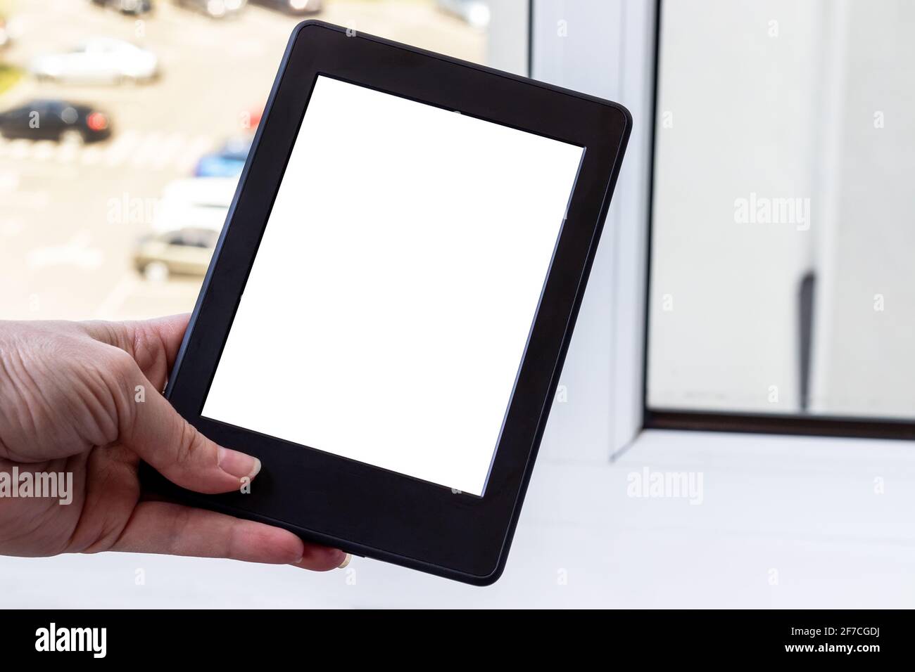 A modern black electronic book with a white blank screen in female hand ...