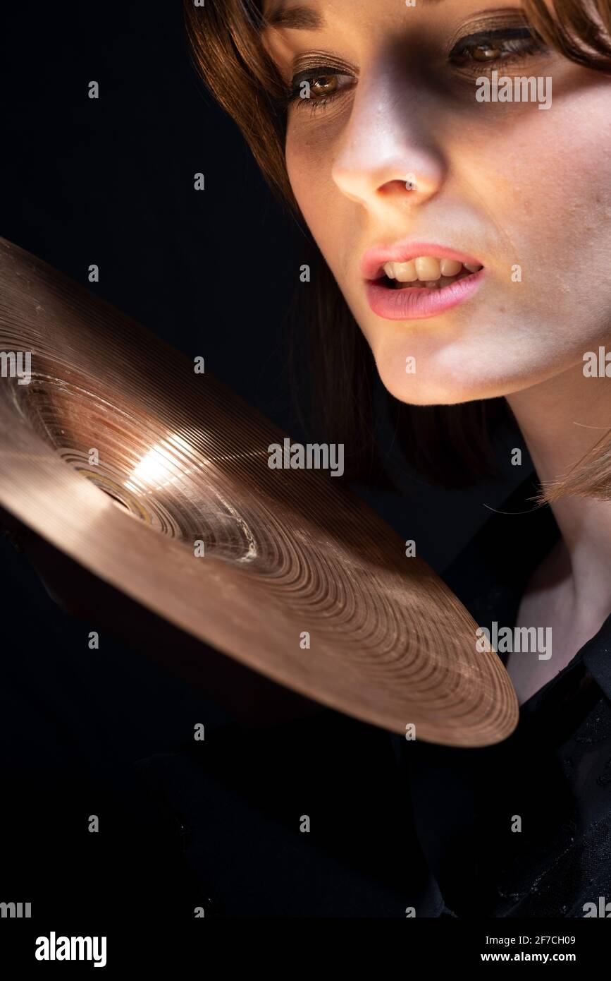 girl model musician in black, holding a snare drum cymbal, looks to the ...