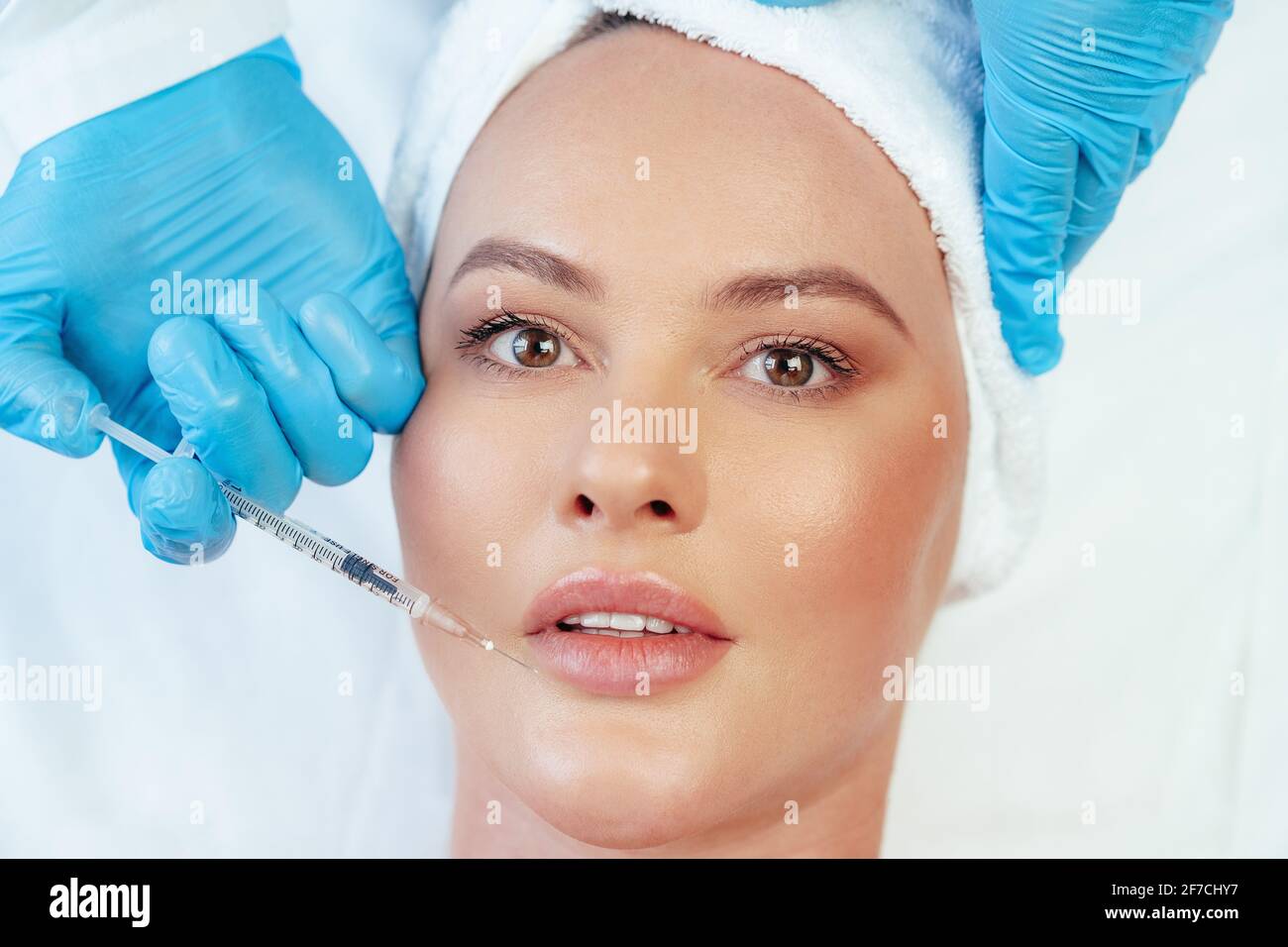 Portrait of a beautiful woman having an injection of botox in her face ...