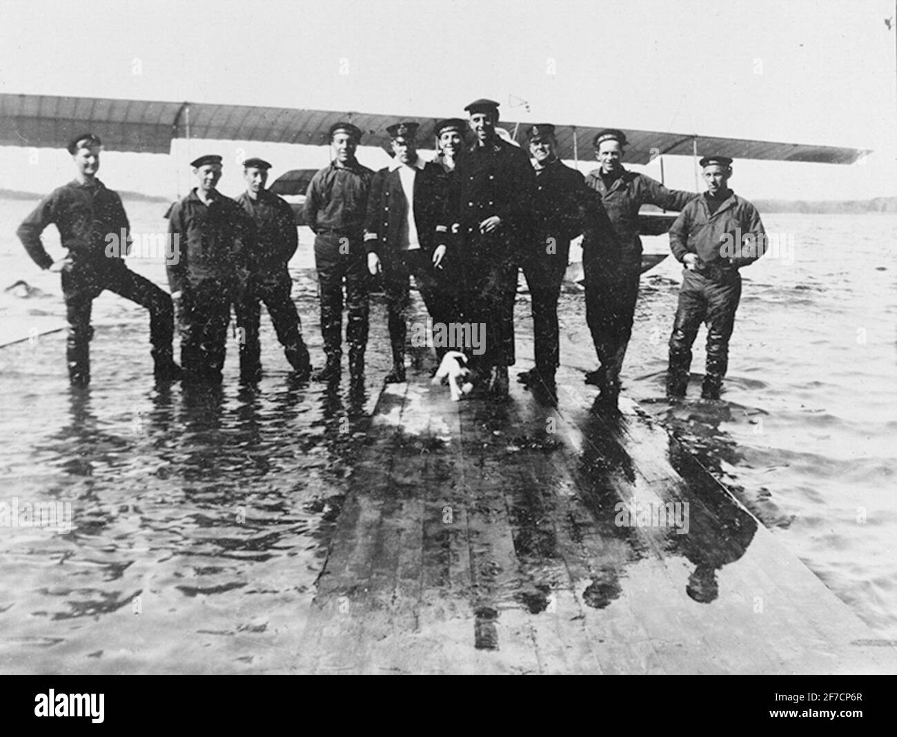 Ten men from the navy and a dog at the slip in front of a sea flying ...