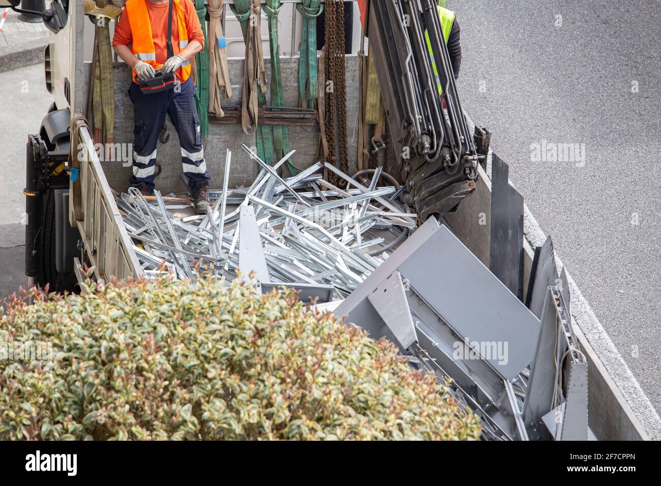Worker operating a crane loading a truck with metallic scrap. Metal ...