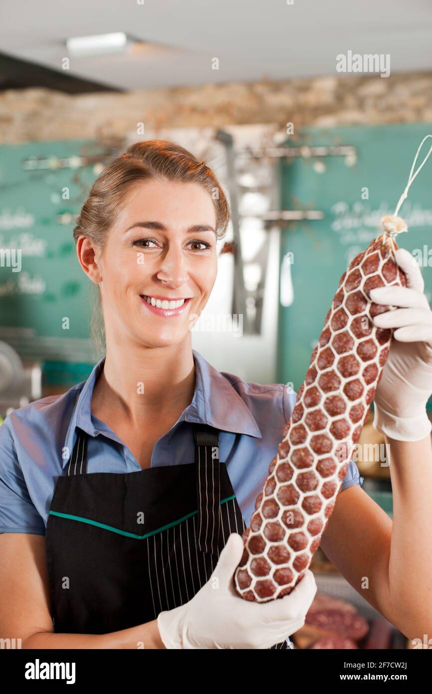 Working in a butchers shop - shop assistant with sausage Stock Photo ...