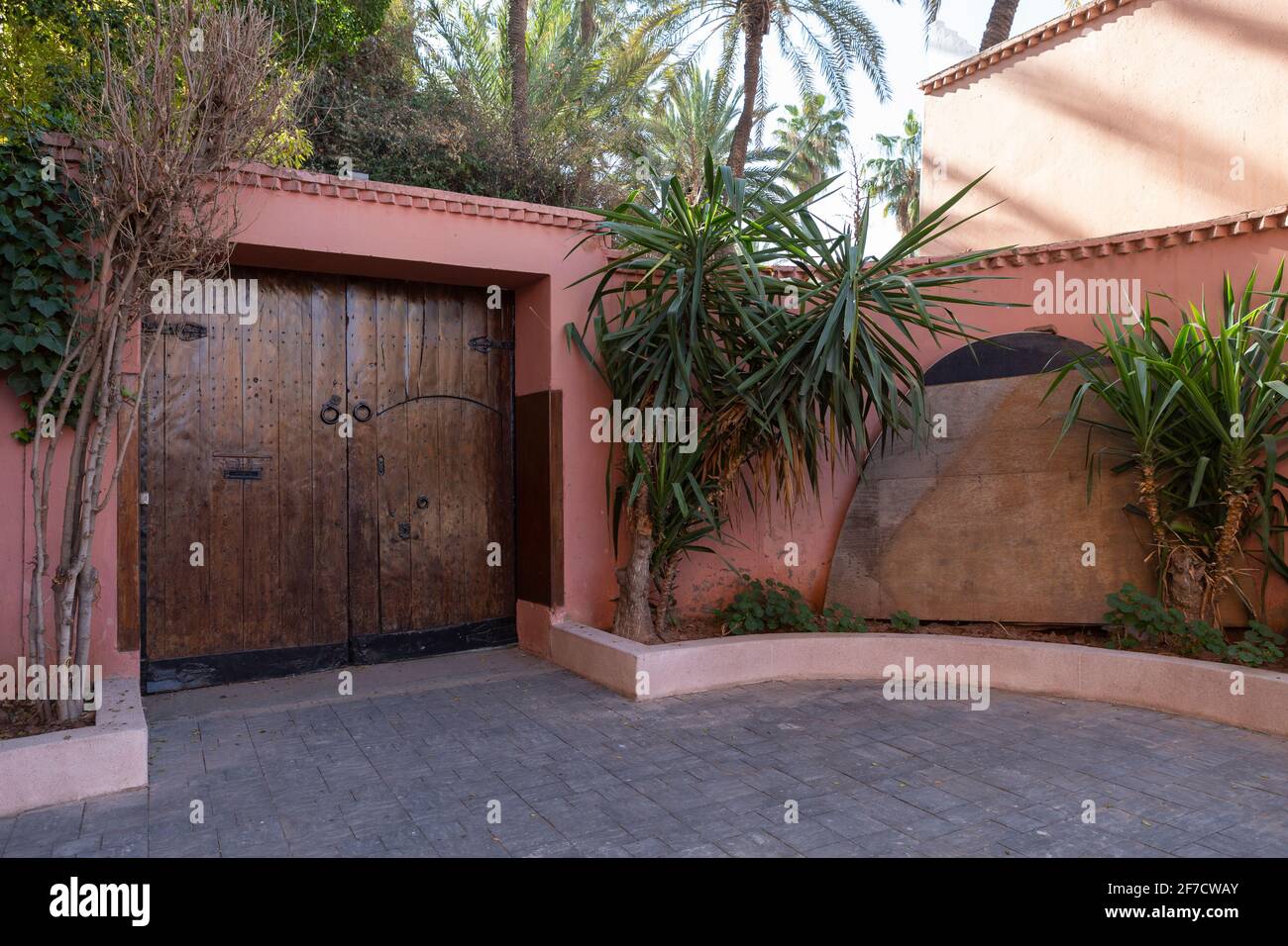 Wooden gate in a reddish painted wall with a wide doorway in the front ...