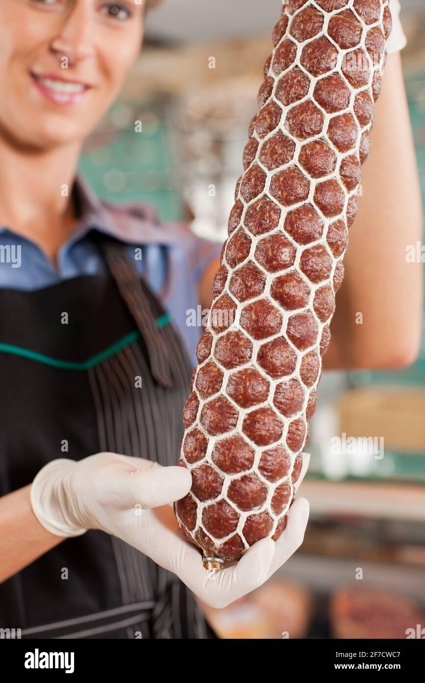 Working in a butchers shop - shop assistant with sausage Stock Photo ...