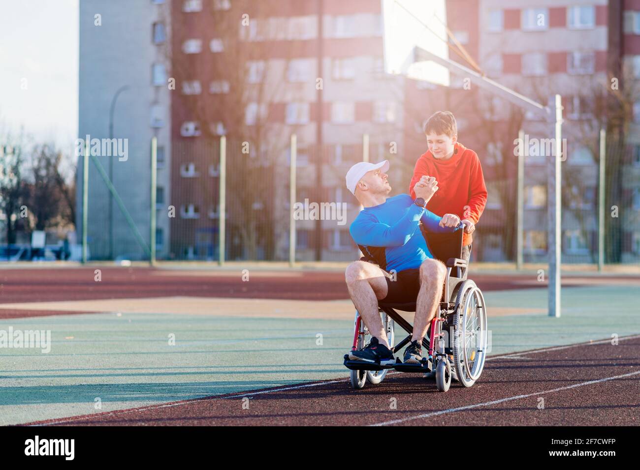 Disabled athlete in wheelchair giving high-five to son on athletics ...