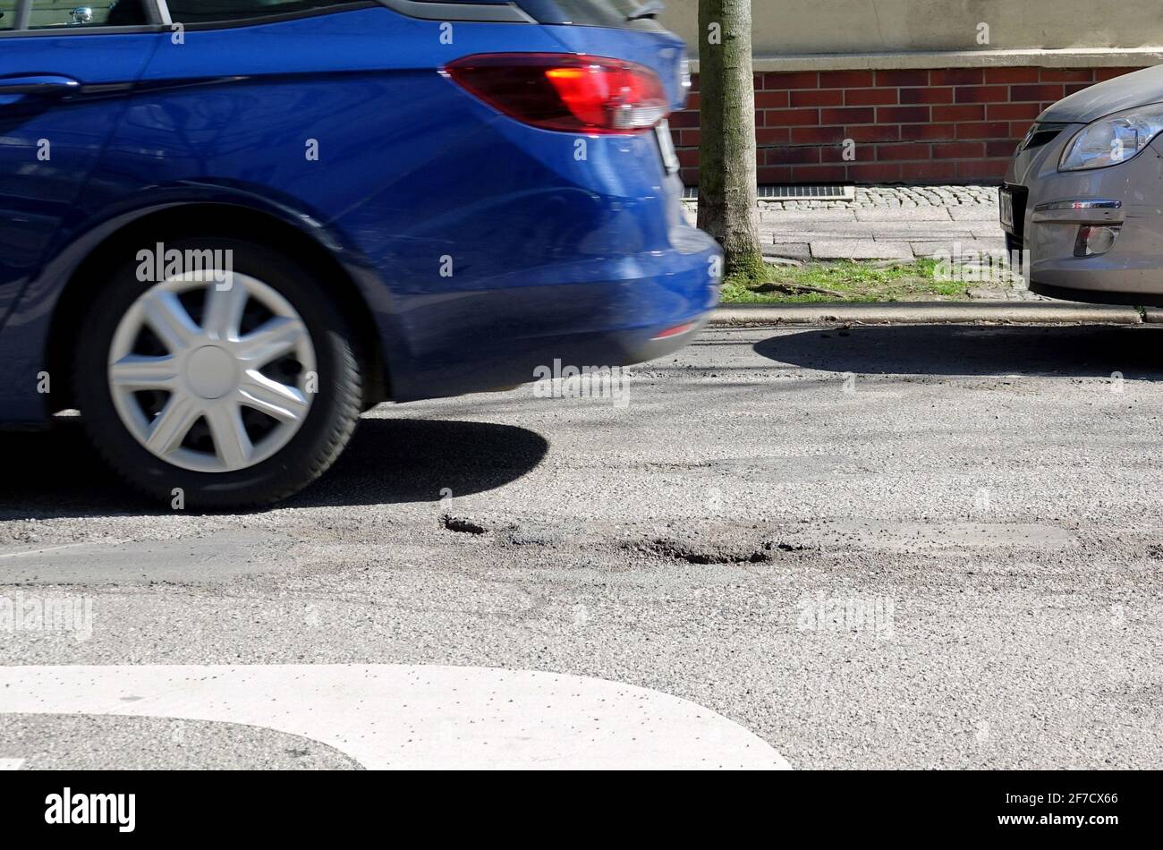 Berlin, Germany. 30th Mar, 2021. A car drives past damage in the road ...
