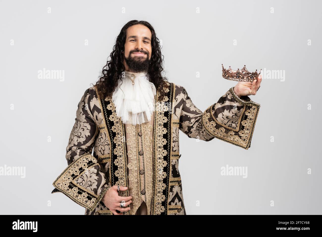 pleased hispanic king in medieval clothing holding golden crown while ...