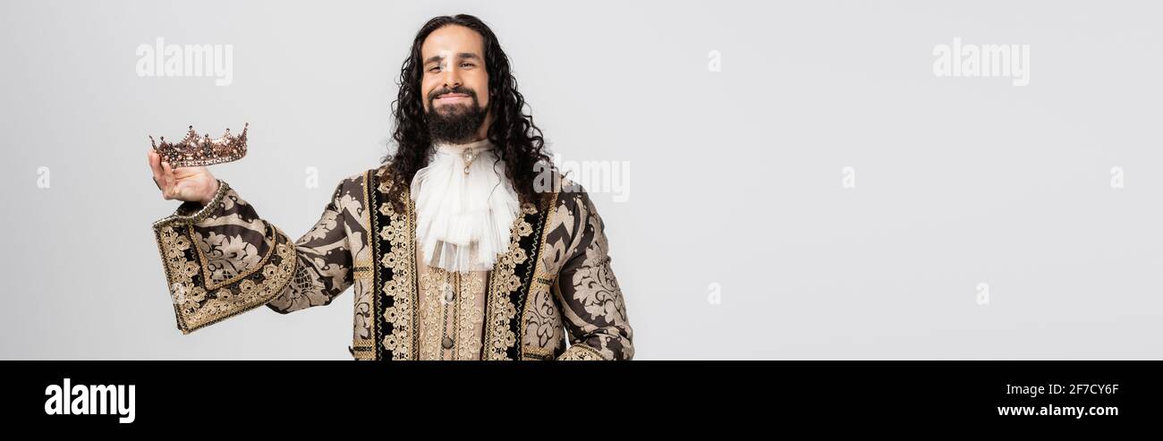 pleased hispanic king in medieval clothing holding golden crown while ...