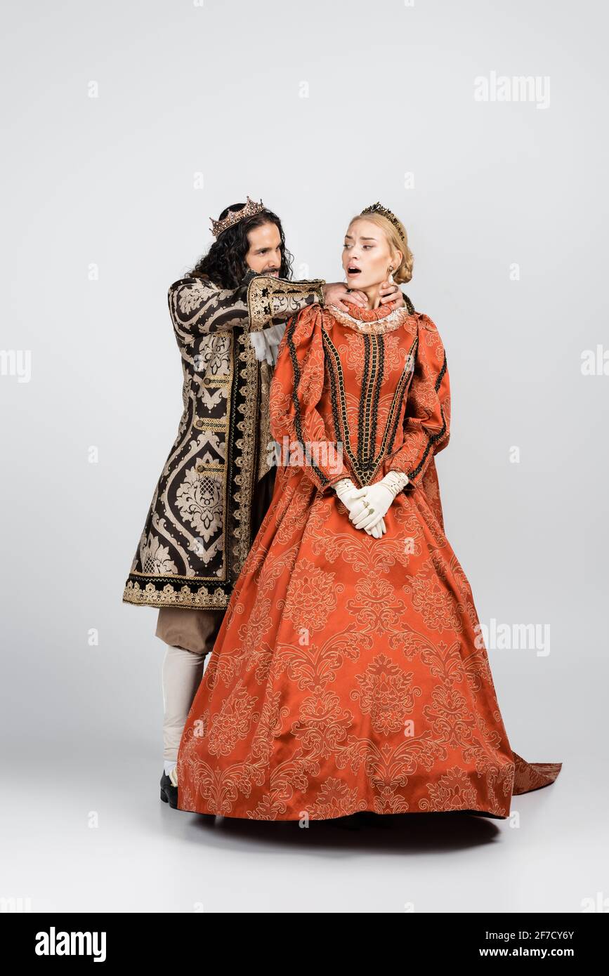 full length of hispanic king in medieval clothing choking shocked queen ...