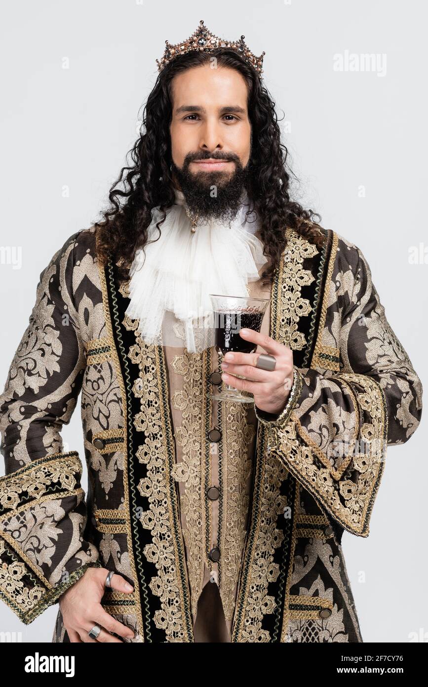 hispanic king in medieval clothing and golden crown holding glass of ...