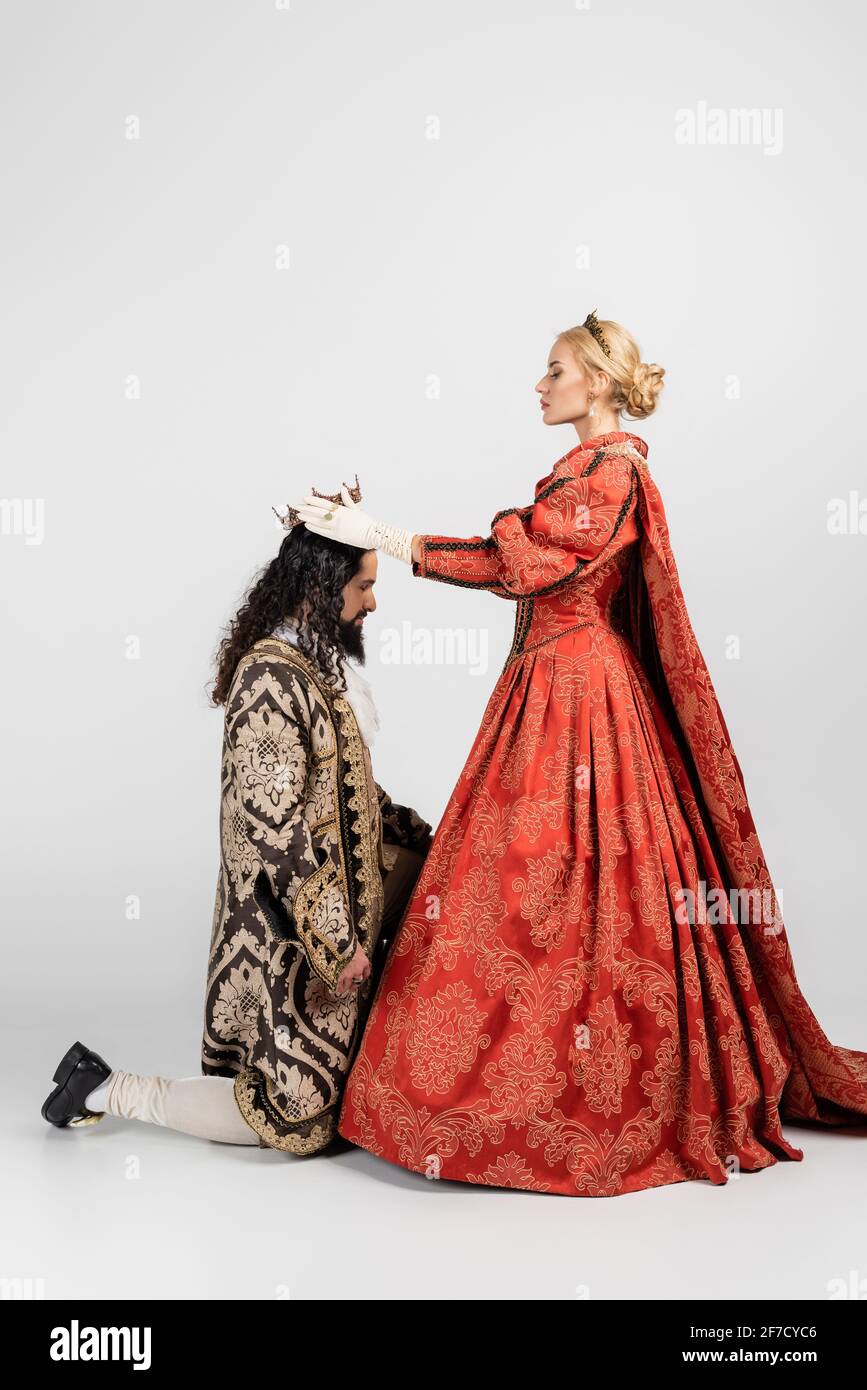 side view of blonde queen wearing crown on hispanic king in medieval ...