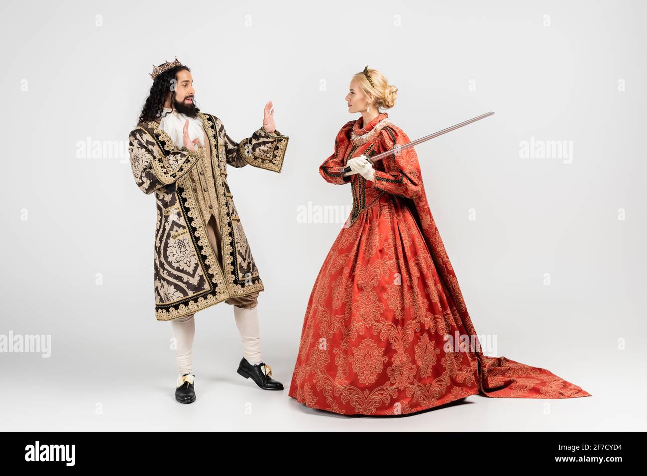 full length of blonde queen holding sword near scared hispanic king in ...