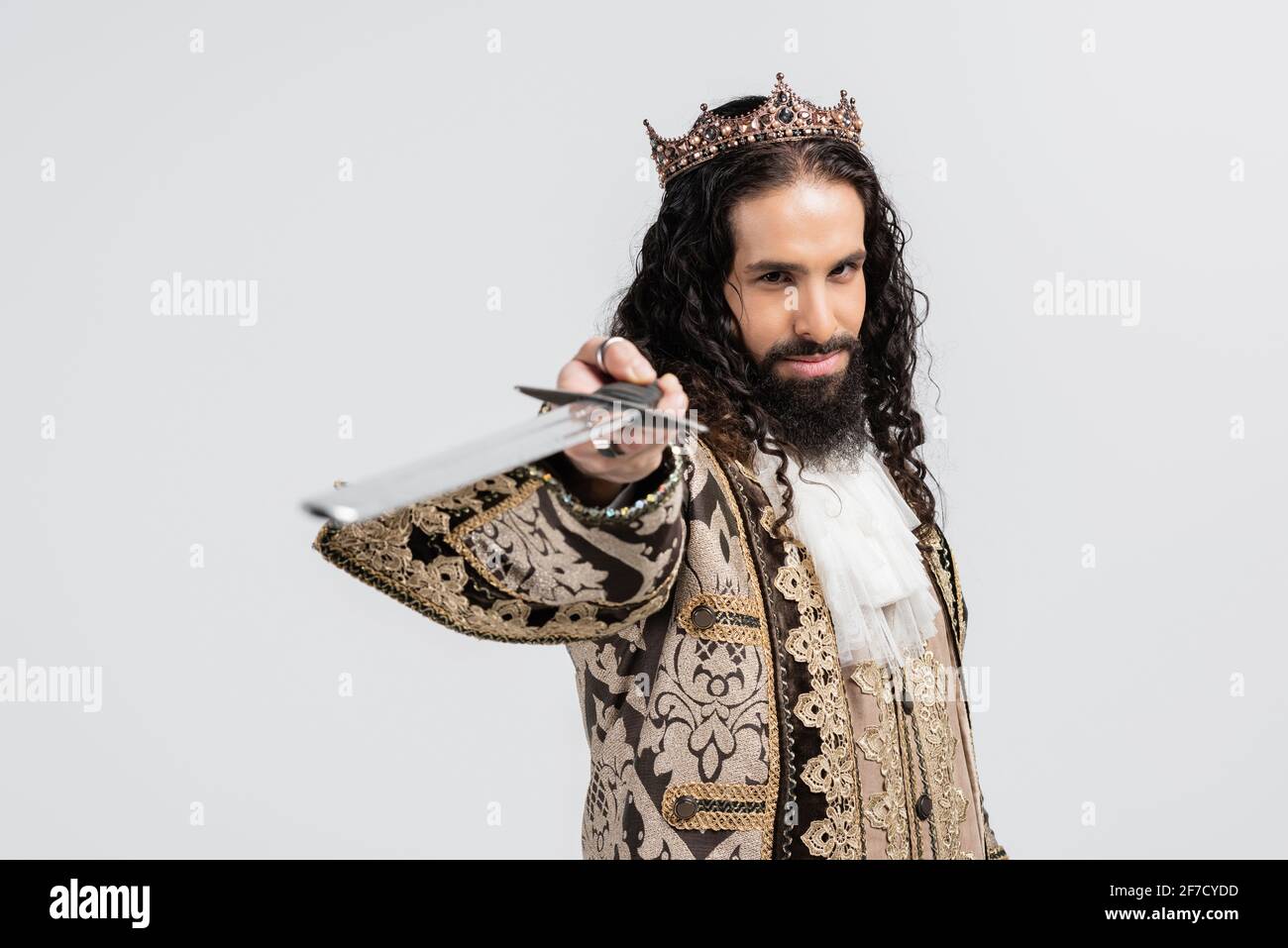 hispanic king in medieval clothing and crown holding blurred sword ...