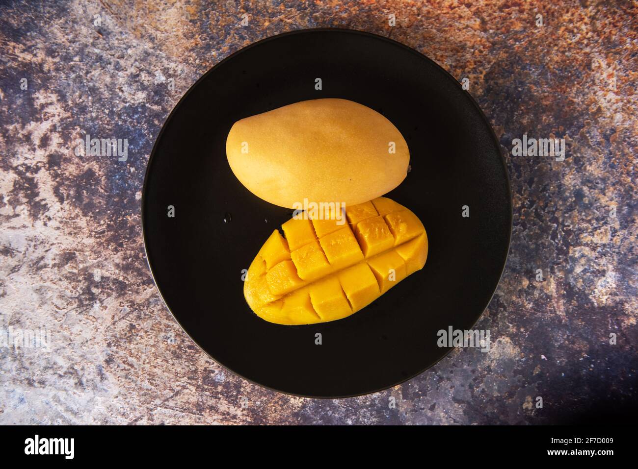 Fresh yellow mango fruit in a black plate on grey stone backgrounds ...