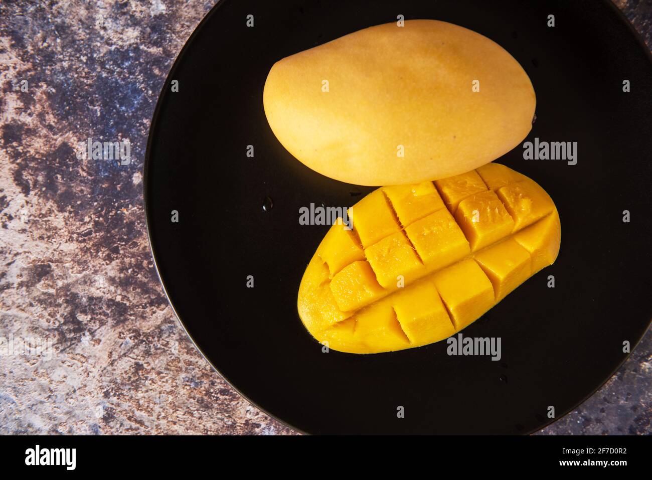 Fresh yellow mango fruit in a black plate on grey stone backgrounds ...