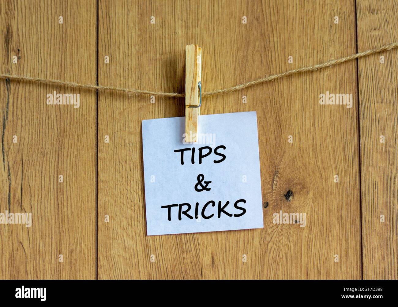 Tips and tricks symbol. White paper on wooden clothespin. Words 'Tips ...