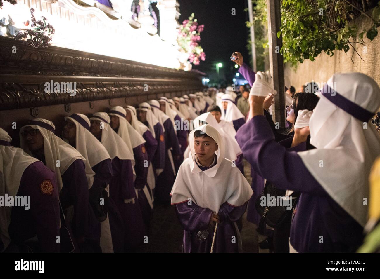 Cucuruchos in purple robes process solemnly through the streets of ...