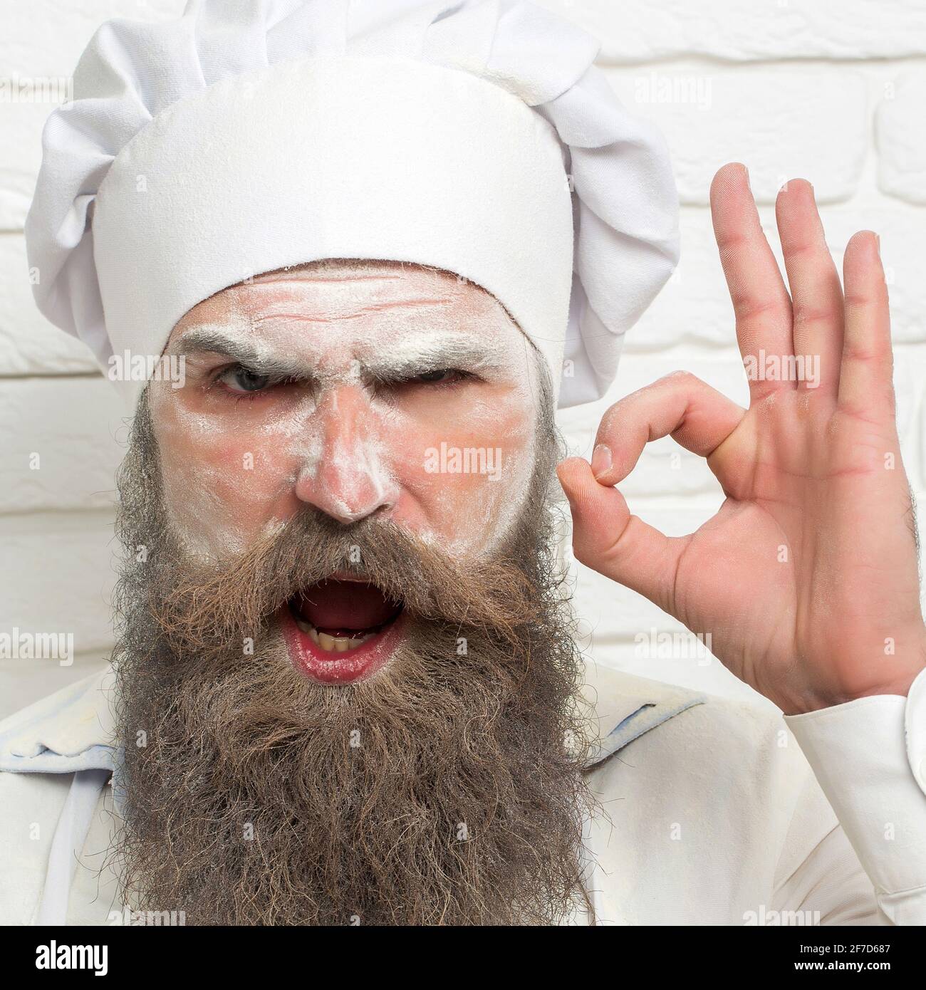 Man with flour on face show OK. Close up portrait of serious baker man ...