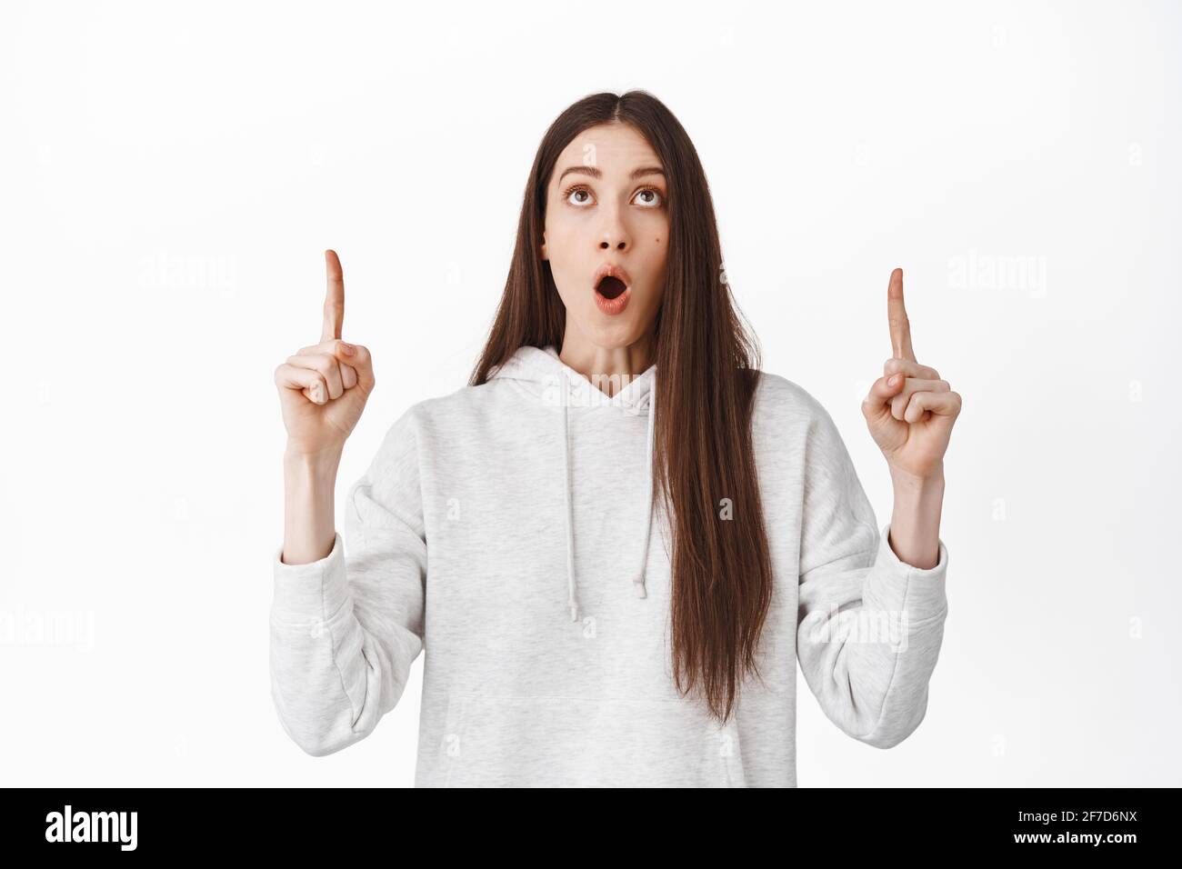 Surprised young caucasian woman pointing and looking up with dropped ...