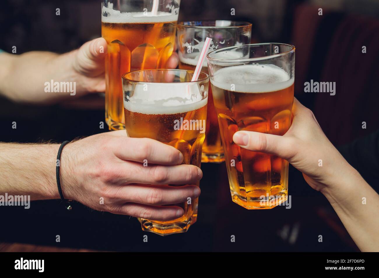 Four friends with a fresh beer in a Beer garden close-up on beer stein ...