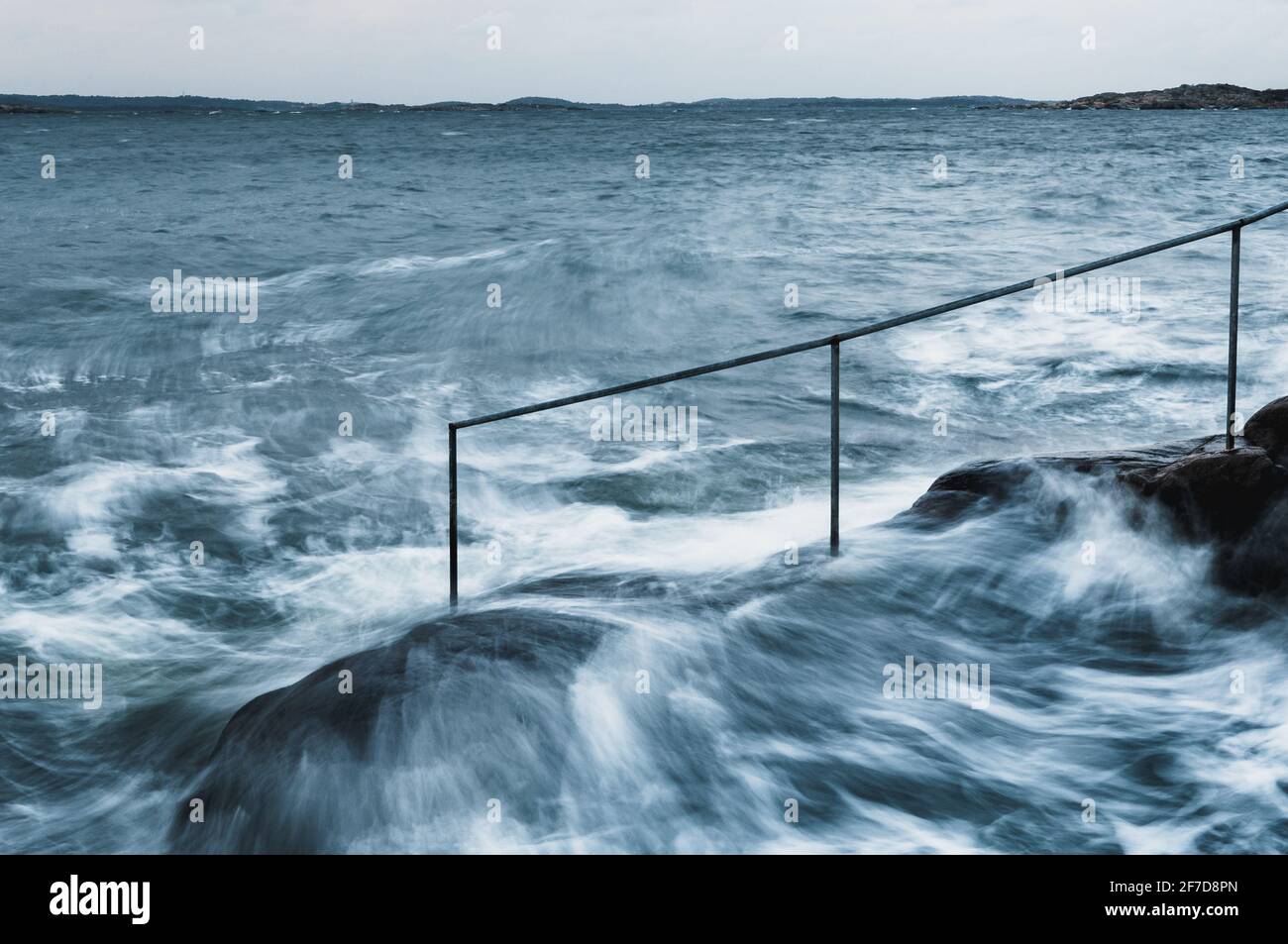 Waves washing over ladder leading into sea Stock Photo - Alamy