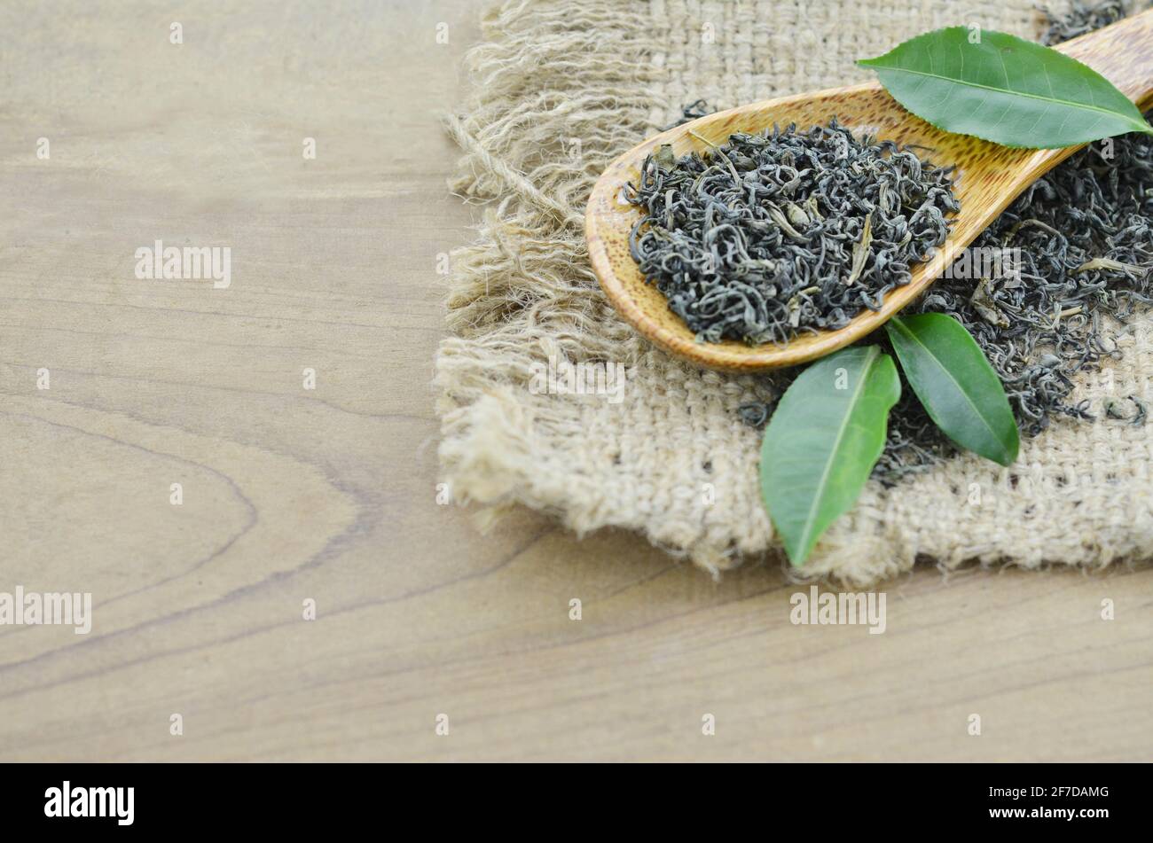 Dry green tea in spoon on wooden background Stock Photo - Alamy