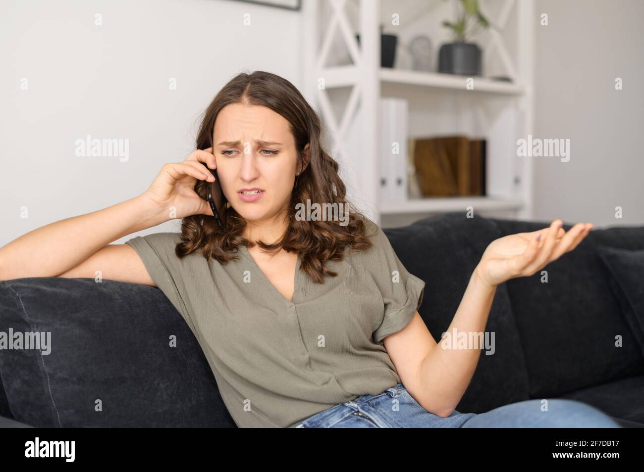 Annoyed woman talks over smartphone at home, irritated female has ...