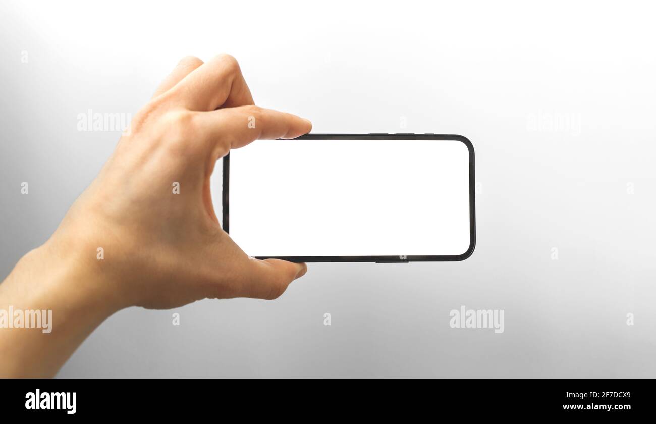 Hand horizontally holding smartphone with blank white screen, mobile ...